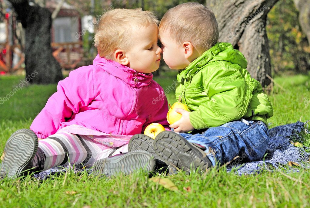 Small children kiss on a green clearing in the autumn — Stock Photo ...