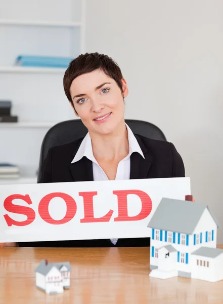 Real estate agent with a sold panel and houses miniatures - Stock Image ...