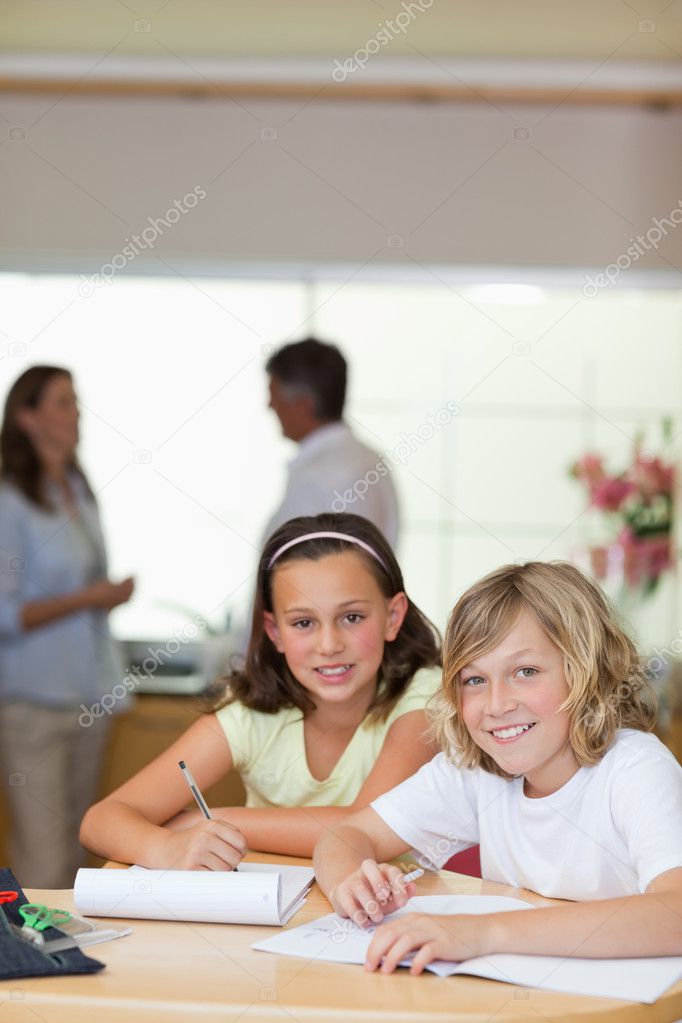 Children doing homework with their parents behind them — Stock Photo ...