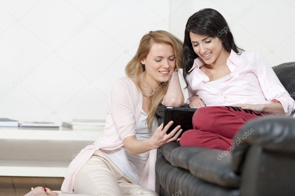 Two friends sharing a computer tablet and chatting Stock Photo by ...