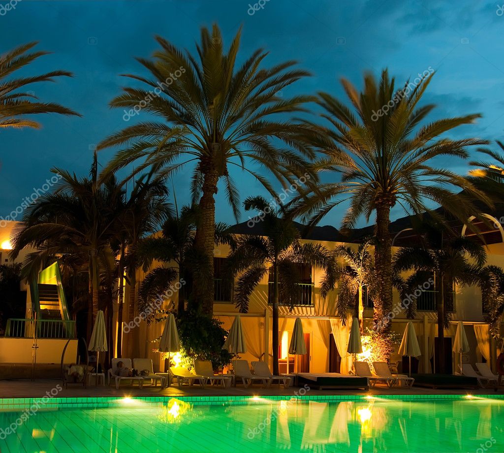 Night swimming pool against the backdrop of palm trees and hotels ...